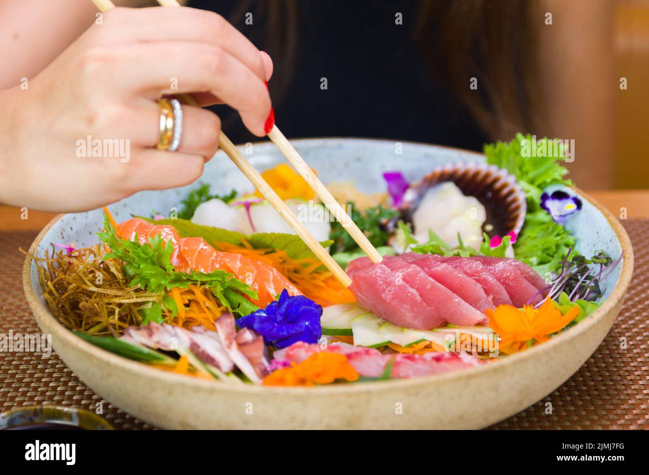 Woman eating delicious sashimi, closeup on chopsticks Stock Photo - Alamy