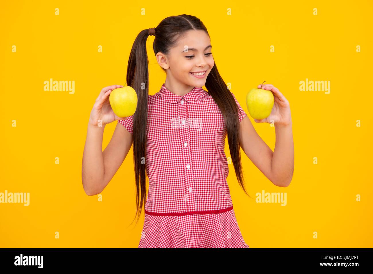 Child girl eating an apple over isolated yellow background. Tennager ...