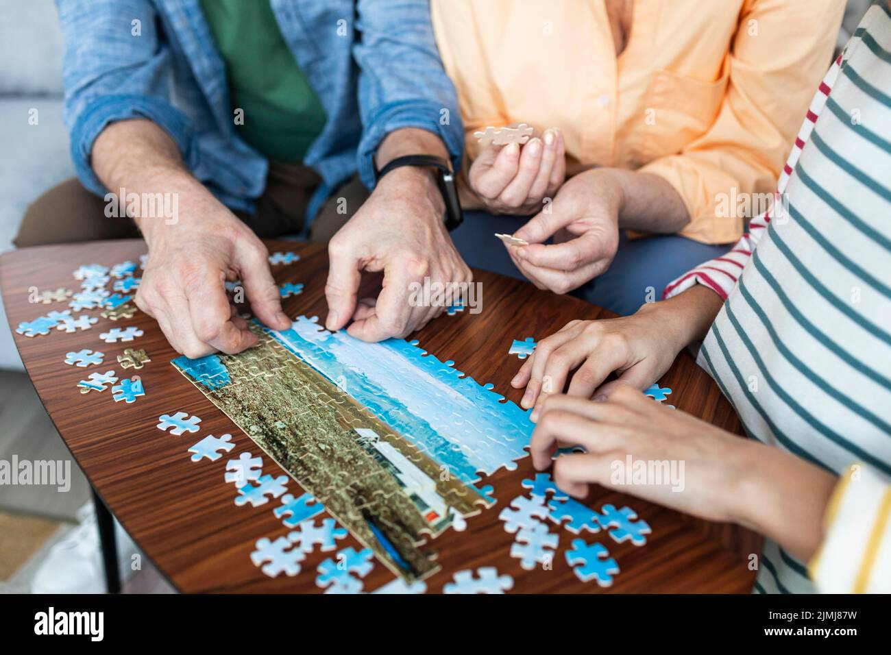 Close up people doing puzzle together Stock Photo - Alamy