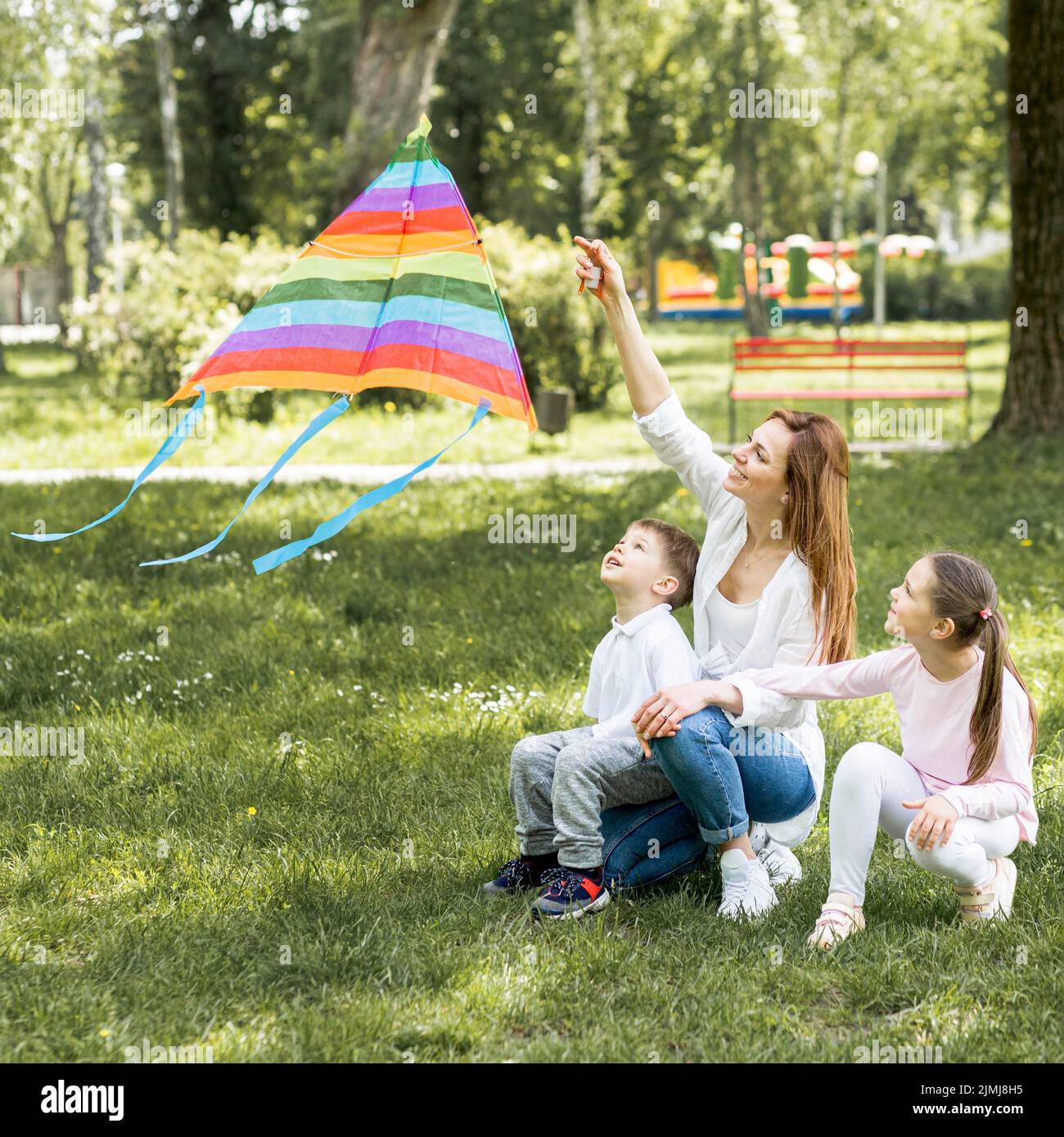 Mother children playing with kite Stock Photo - Alamy