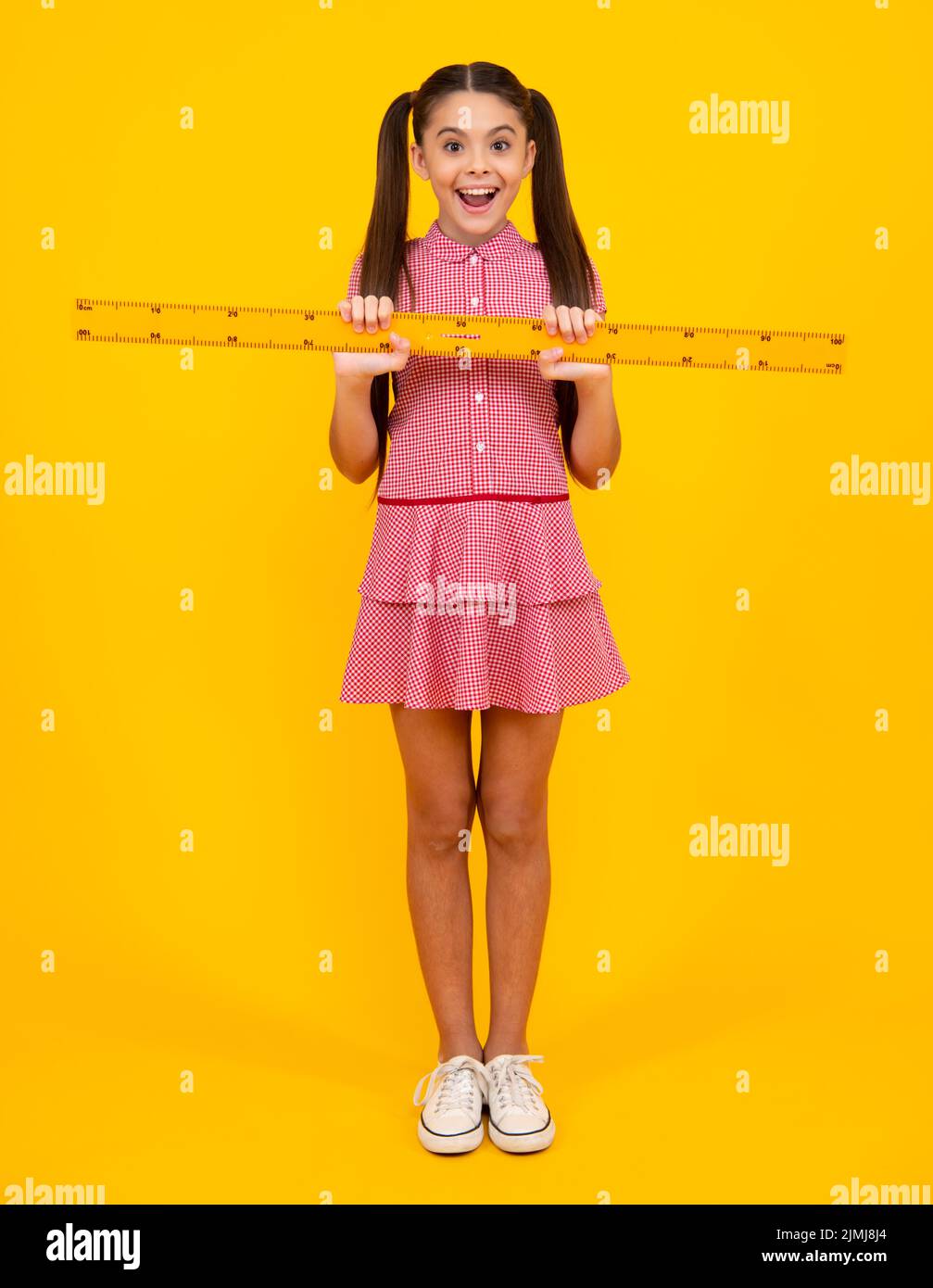 Back to school. School girl hold ruler measuring isolated on yellow ...