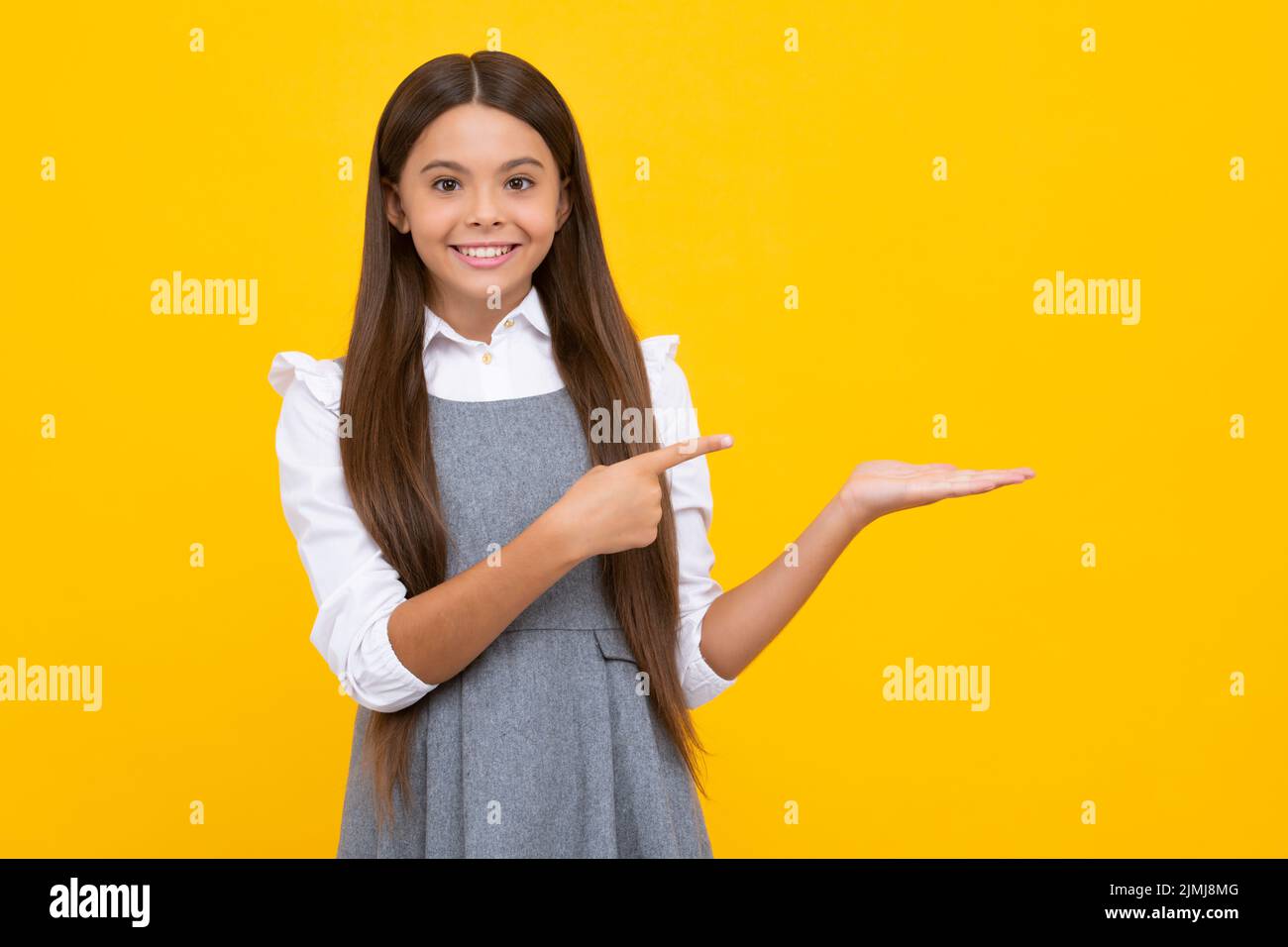 Positive teenager child points aside with cheerful expression, shows ...