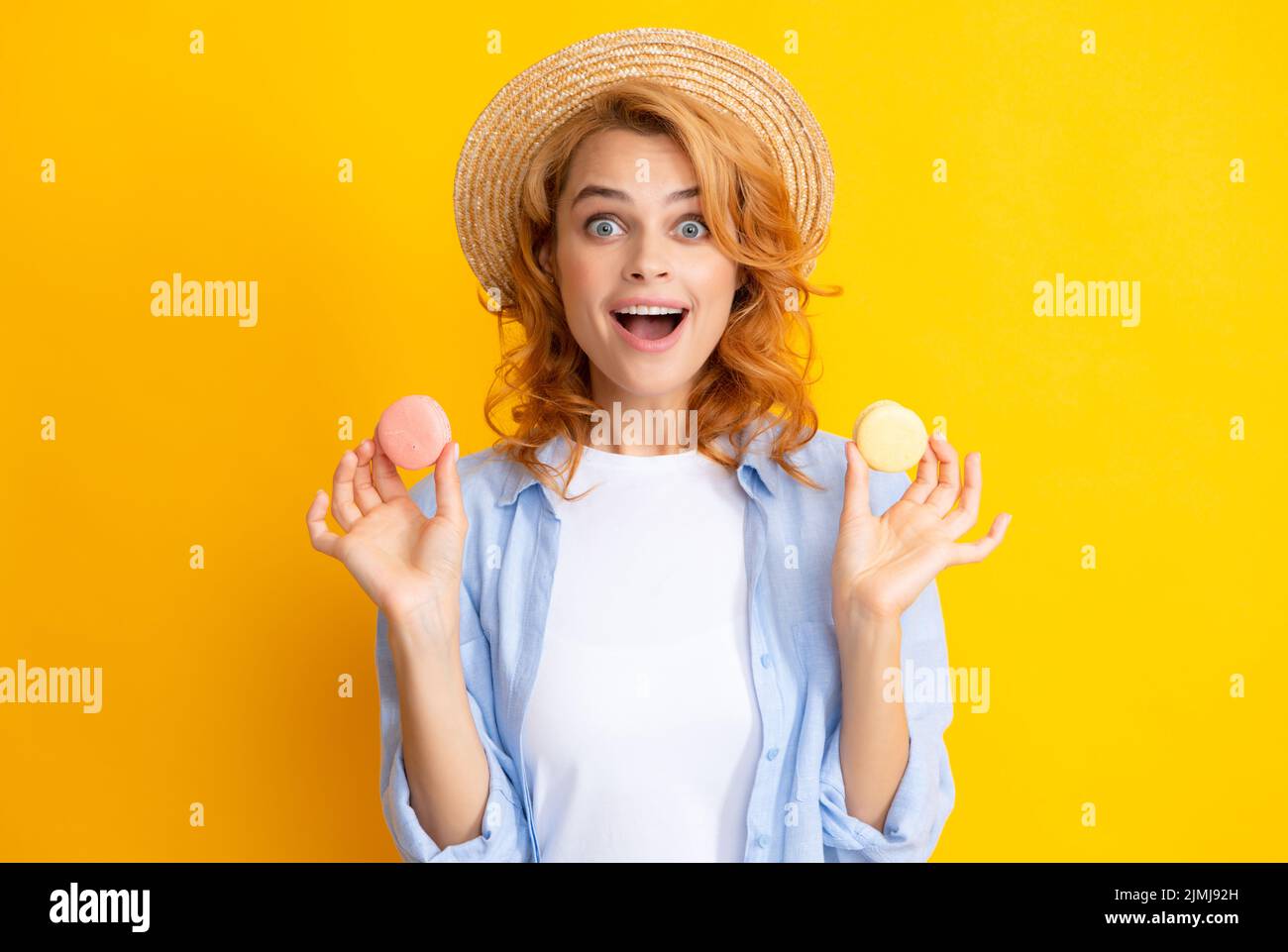 Young pleased woman isolated over yellow background eating macaroons ...