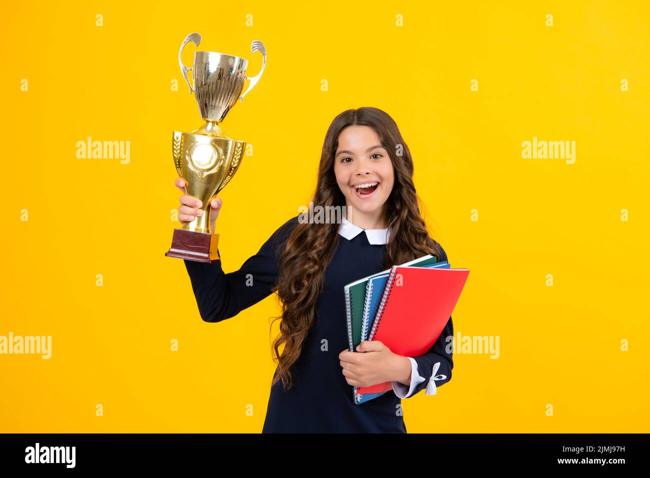 Schoolgirl in school uniform celebrating victory with trophy. Teen ...