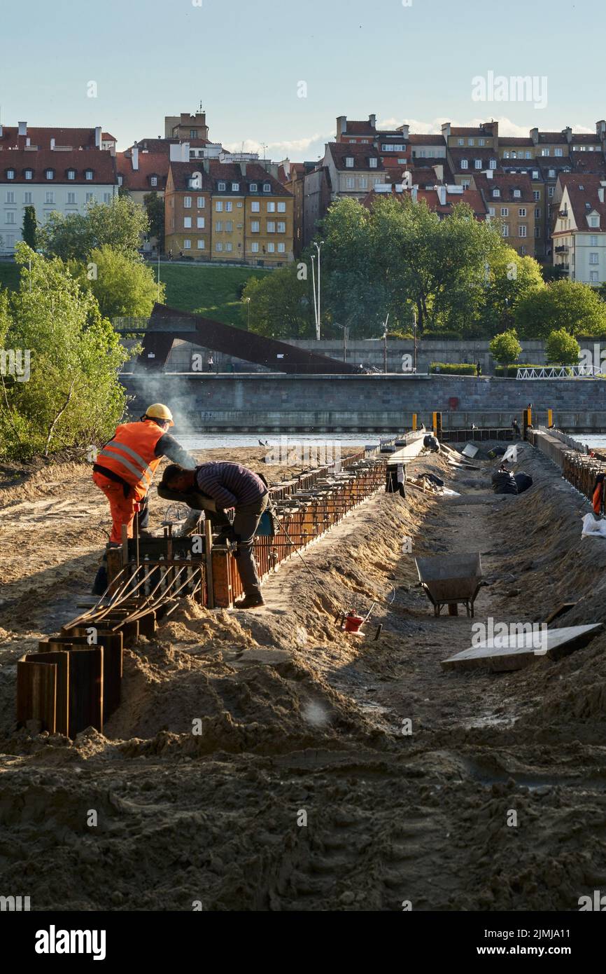 A vertical shot of an old pier under construction with workers in ...