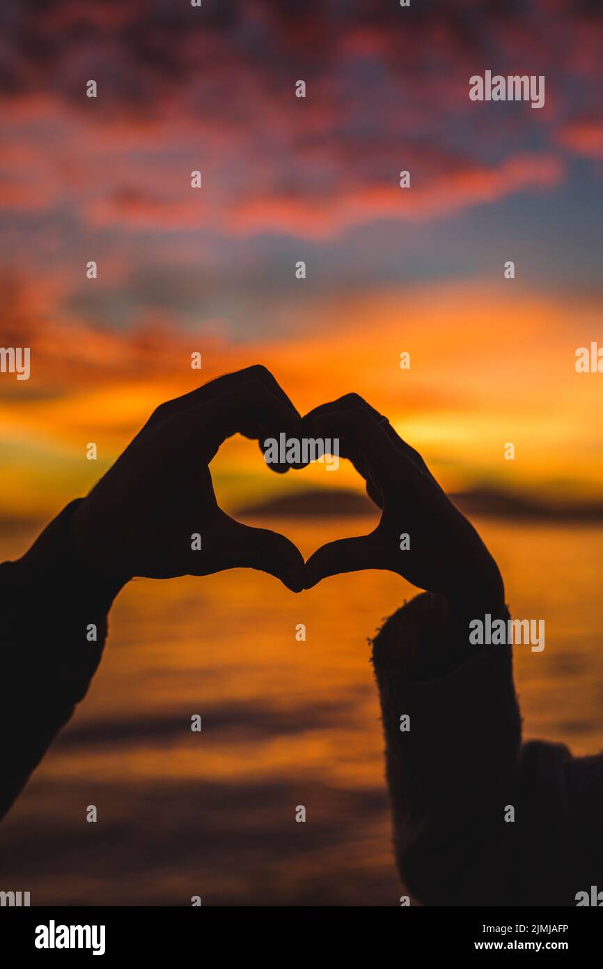Couple making heart from hands sea shore Stock Photo - Alamy