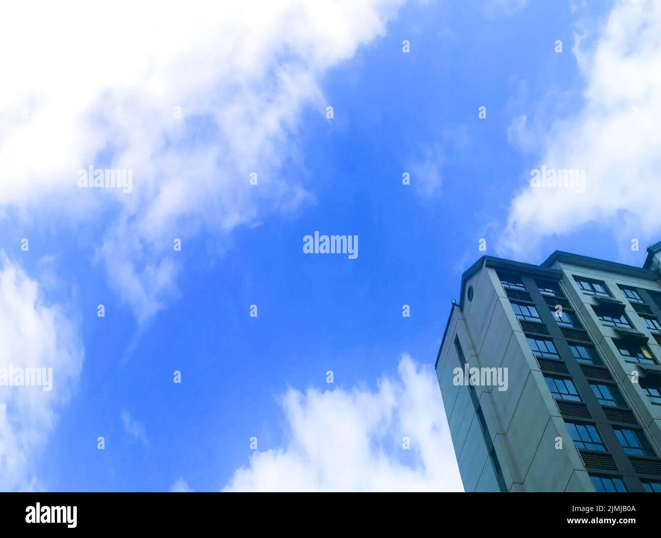 A skyscape of bright blue sky with fluffy white clouds and a modern ...