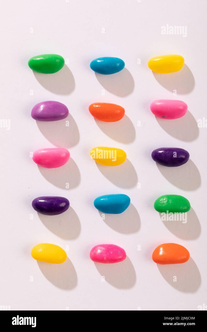 Overhead view of multi colored candies in a row over white background ...
