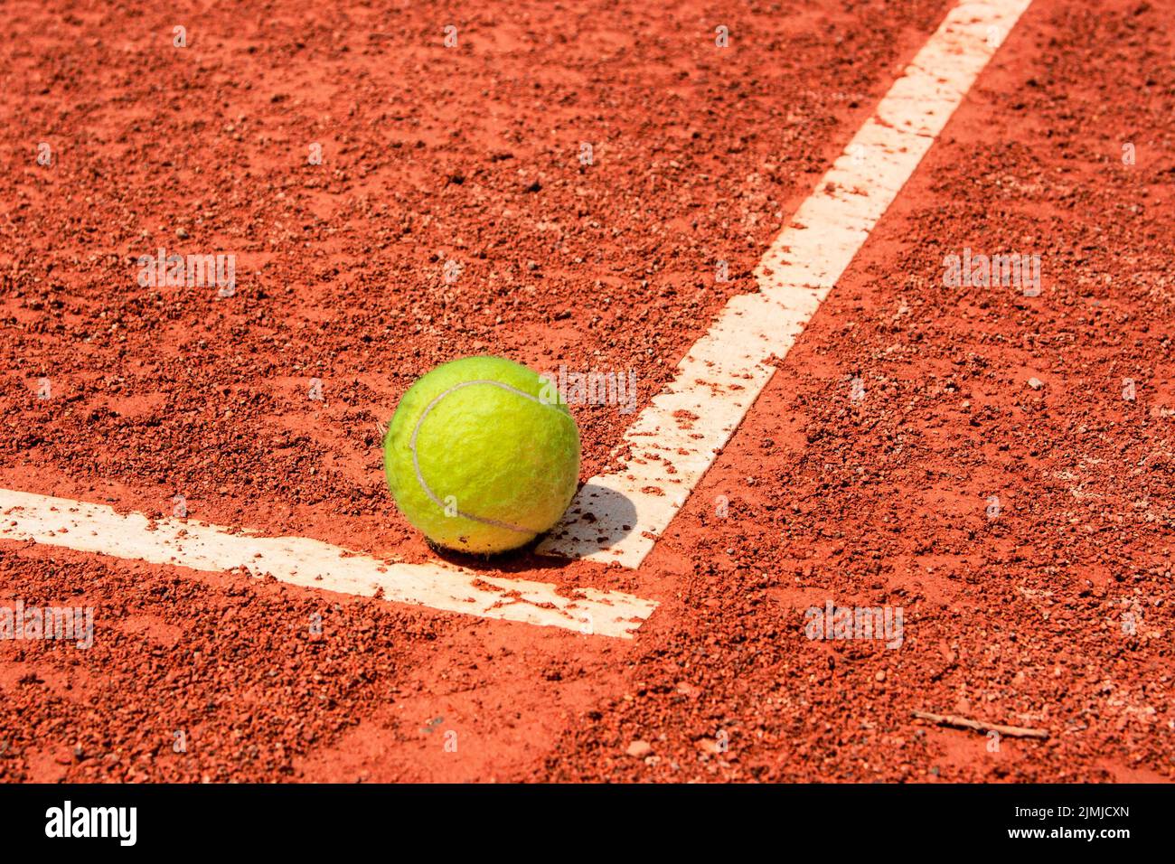A tennis ball on a dirt court. Bright sunny day. Vivid colors and lines ...