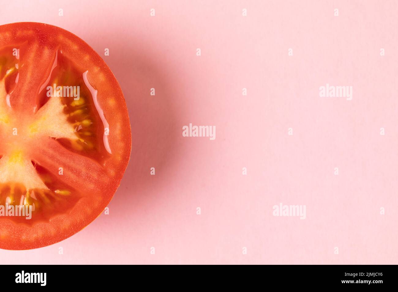 Overhead view of fresh halved tomato cross section by copy space on ...
