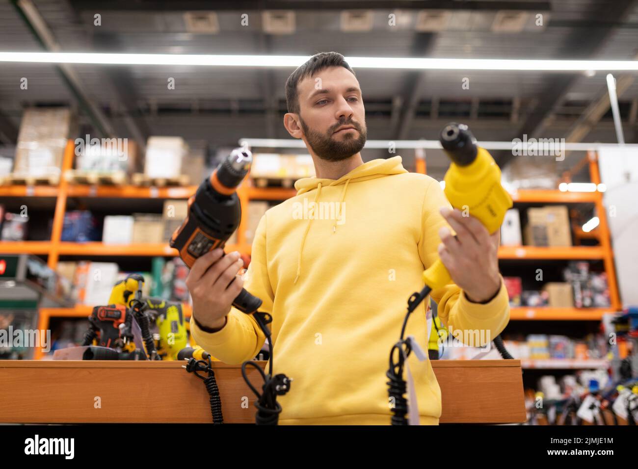 A man chooses a drill for himself as a gift in a construction equipment ...