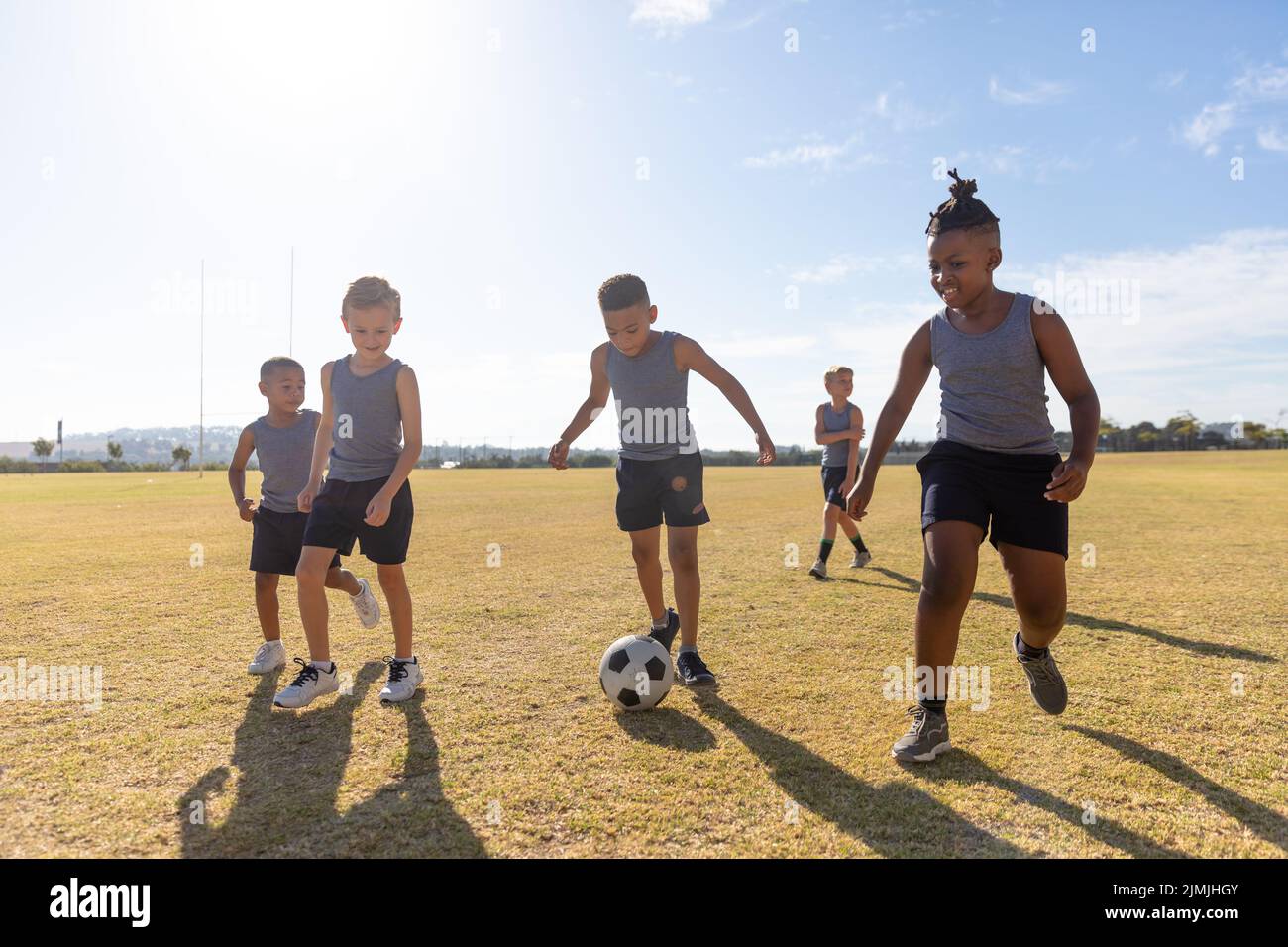Multiracial elementary schoolboys playing soccer on school soccer field ...