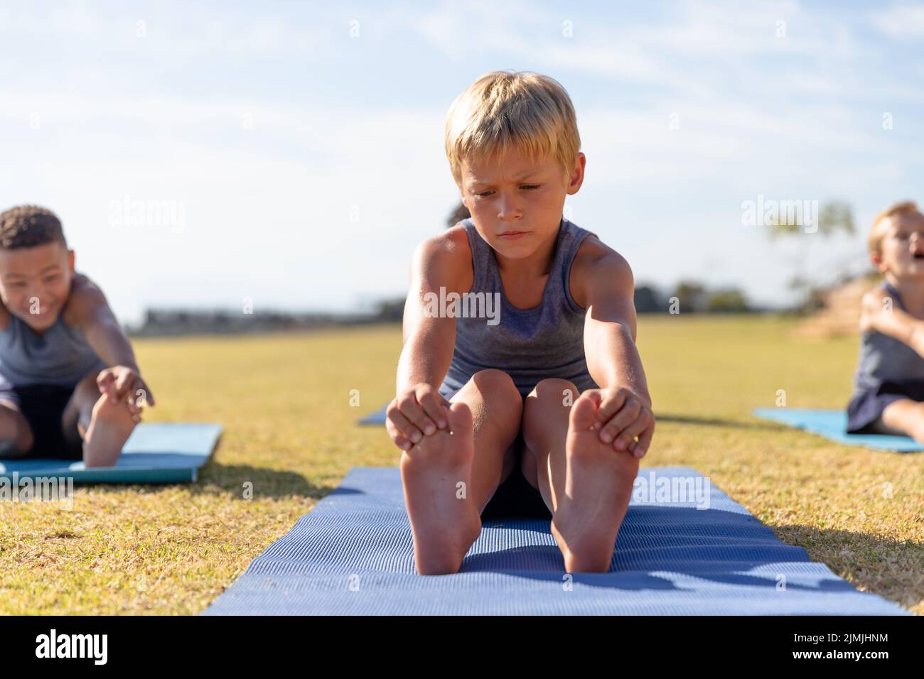 Multiracial elementary schoolboys touching toes while exercising on ...