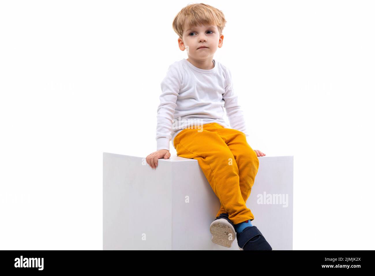 Sad bored blond boy sitting on white background Stock Photo - Alamy