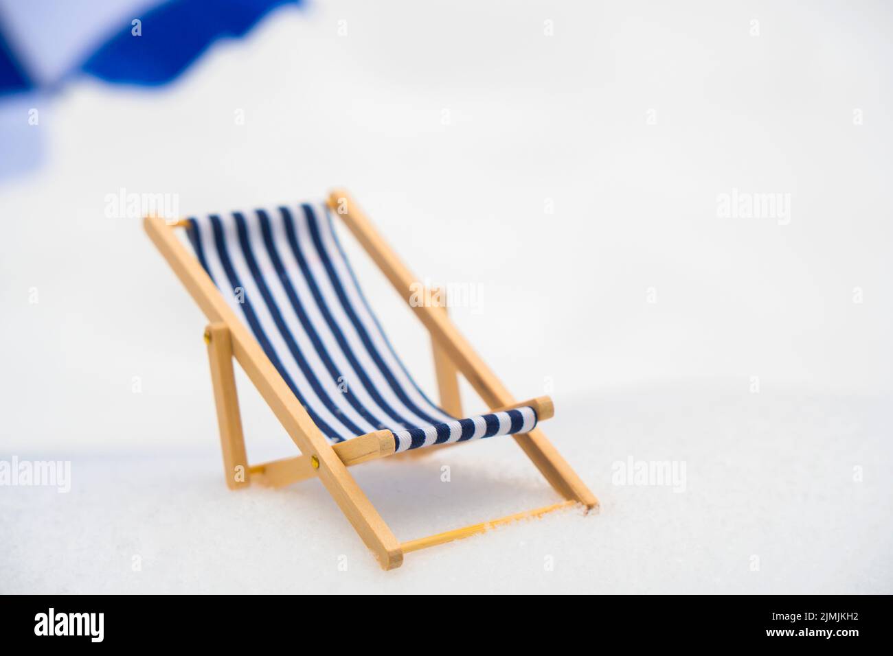 A blue, wooden, striped wooden beach chair in the snow Stock Photo - Alamy