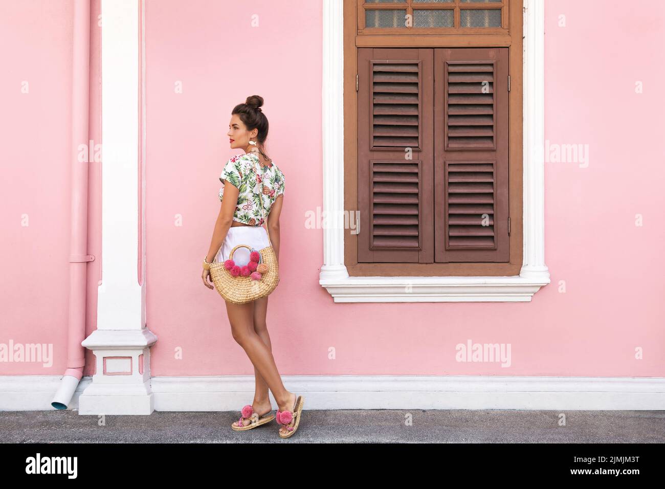 Beautiful and stylish woman posing beside the house with a pink wall ...