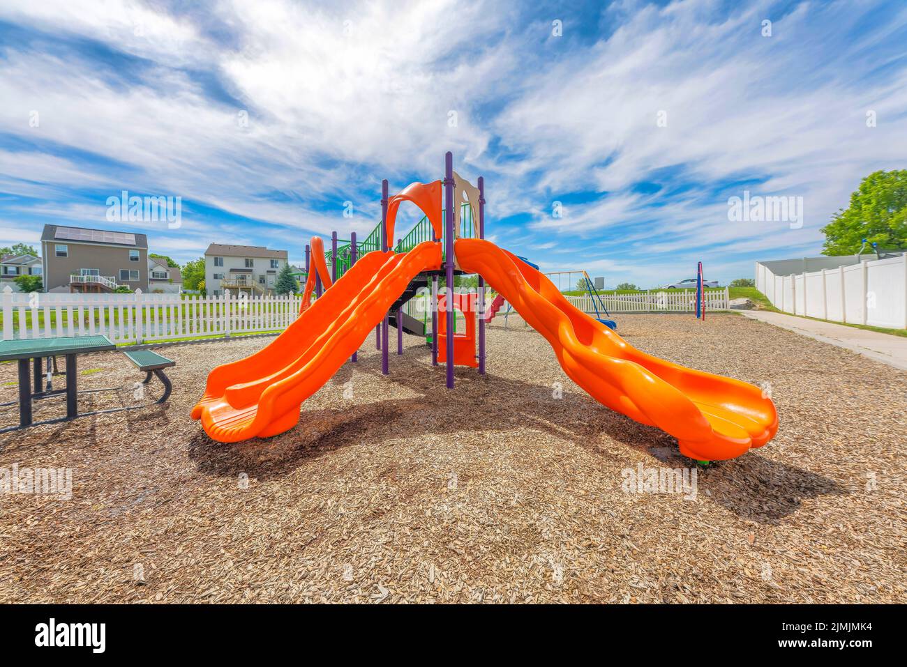 Orange slides in a small playground with picnic table and picket fence ...