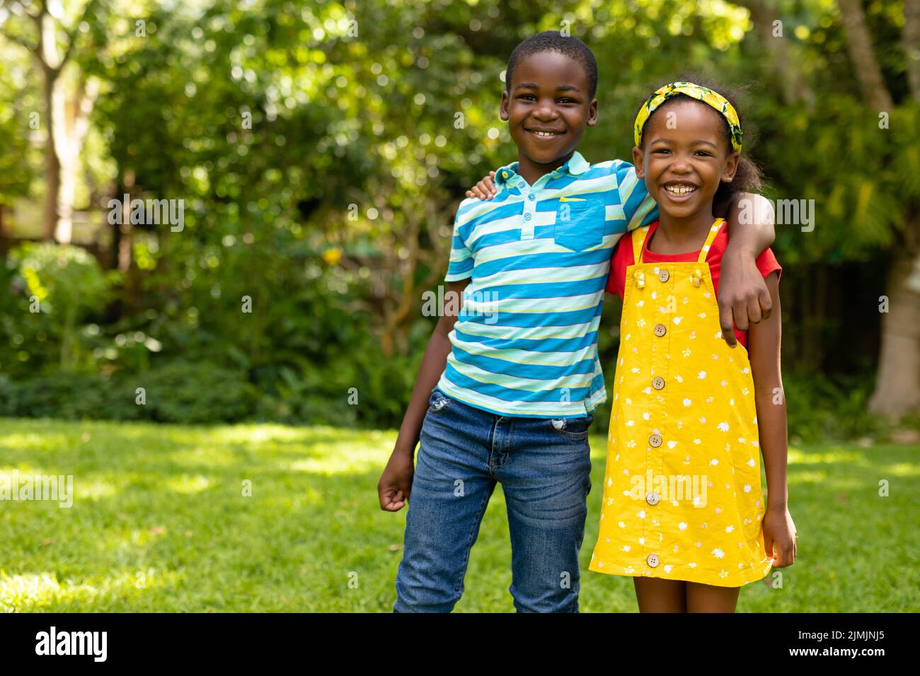 Portrait of smiling african american boy and girl standing with arms ...