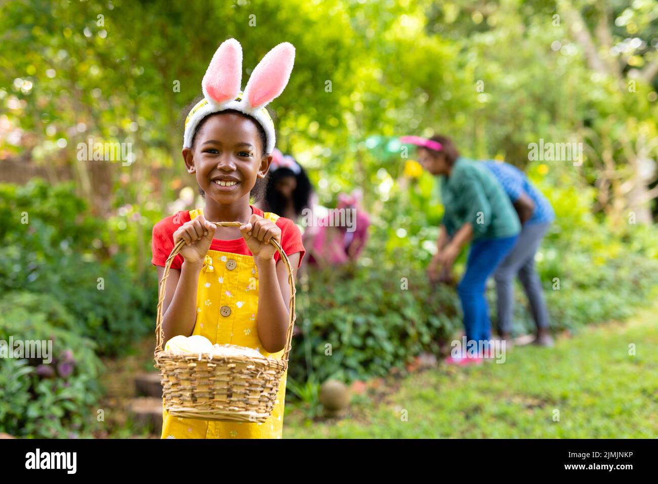 Happy african american girl in bunny ears carrying basket of easter ...