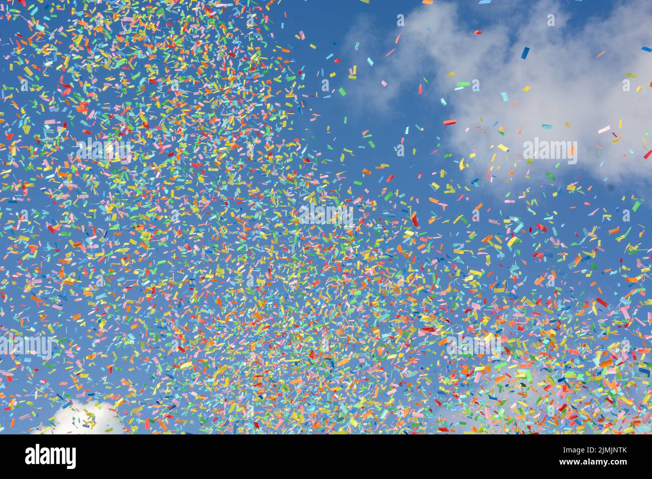 A colorful confetti on the air with blue sky background Stock Photo - Alamy