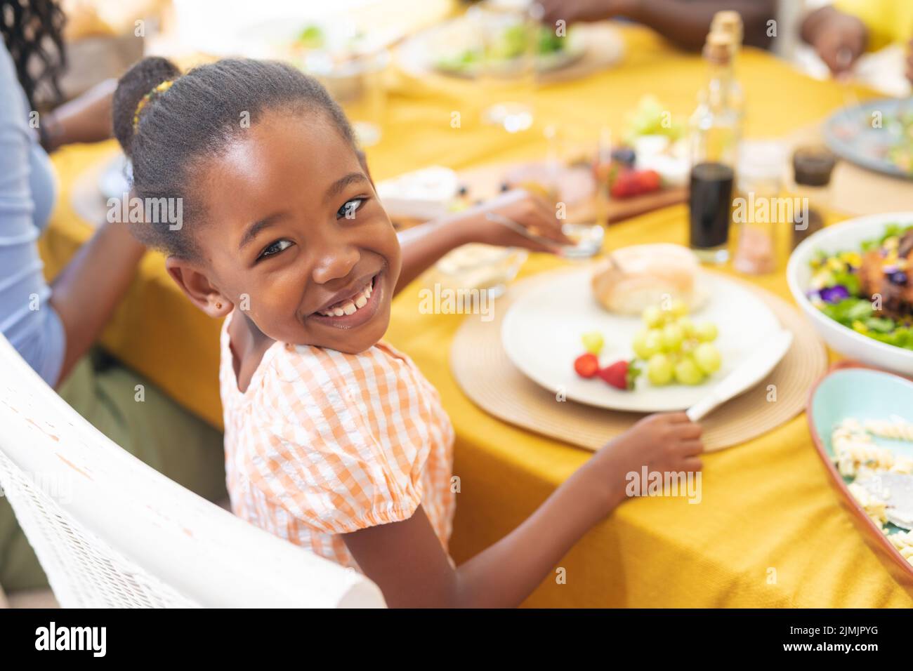 Portrait of smiling african american cute girl having lunch with family ... Portrait of smiling african american cute girl having lunch with family ...