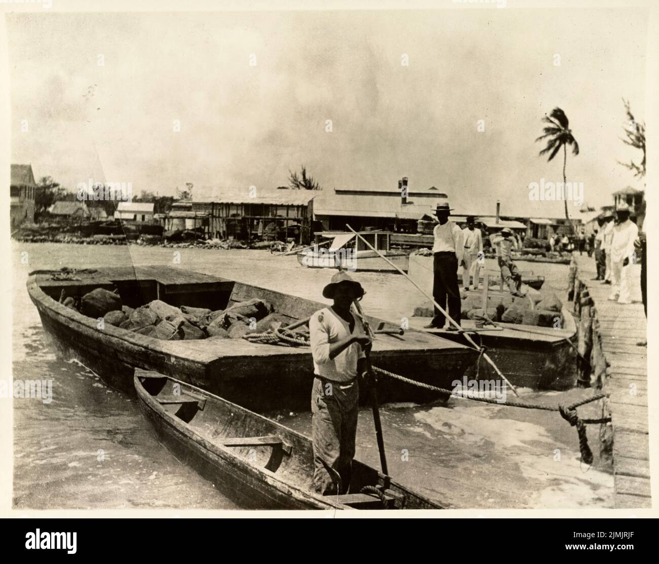 Vintage black and white photograph of men with barge-loads of bundled ...