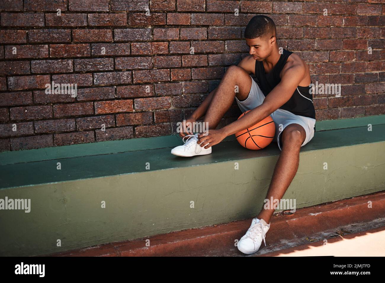 The harder you work, the harder it is to lose. a sporty young man tying ...