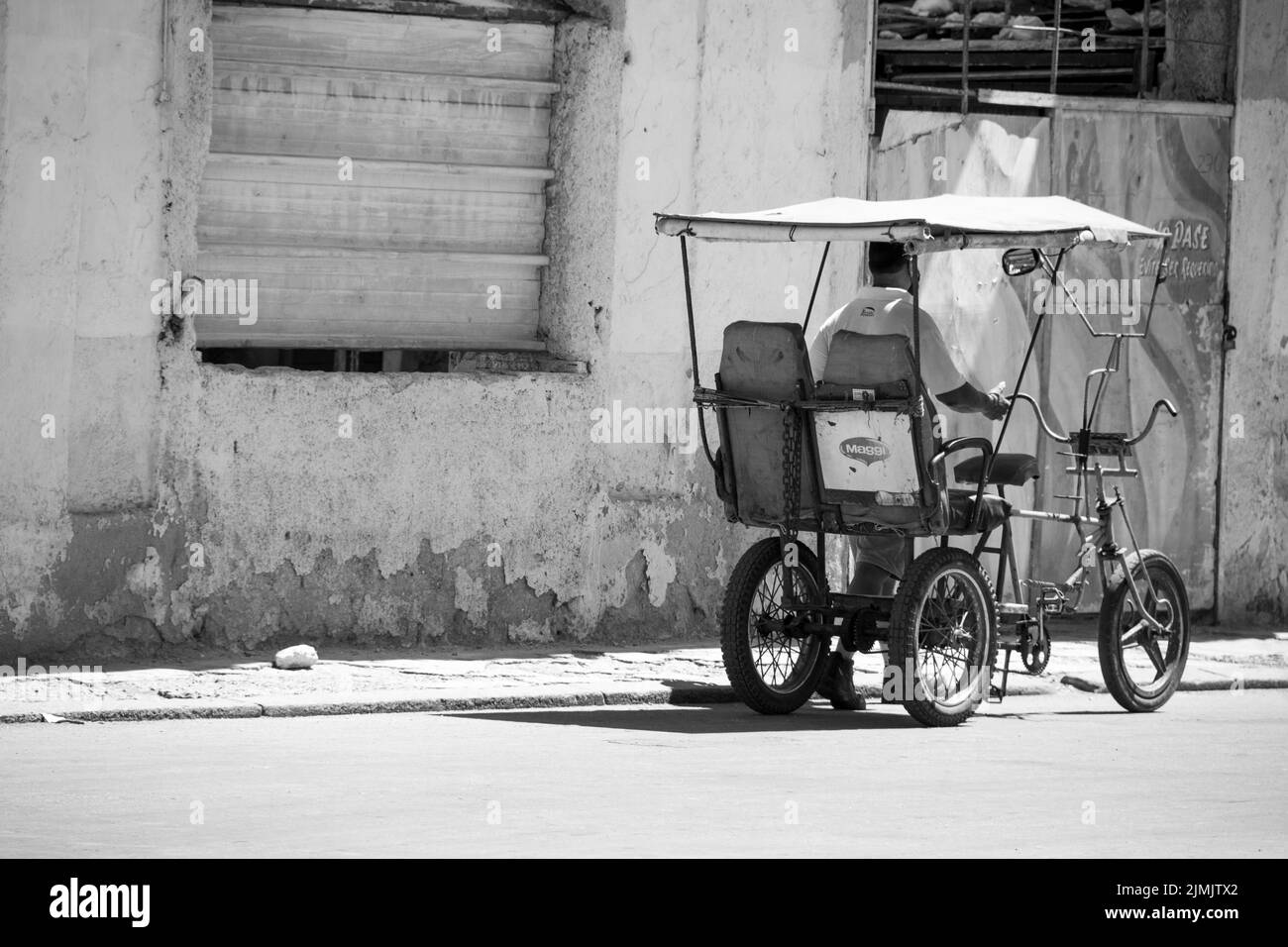 A black and white image of a Cuban taxi driver driving his taxi down ...