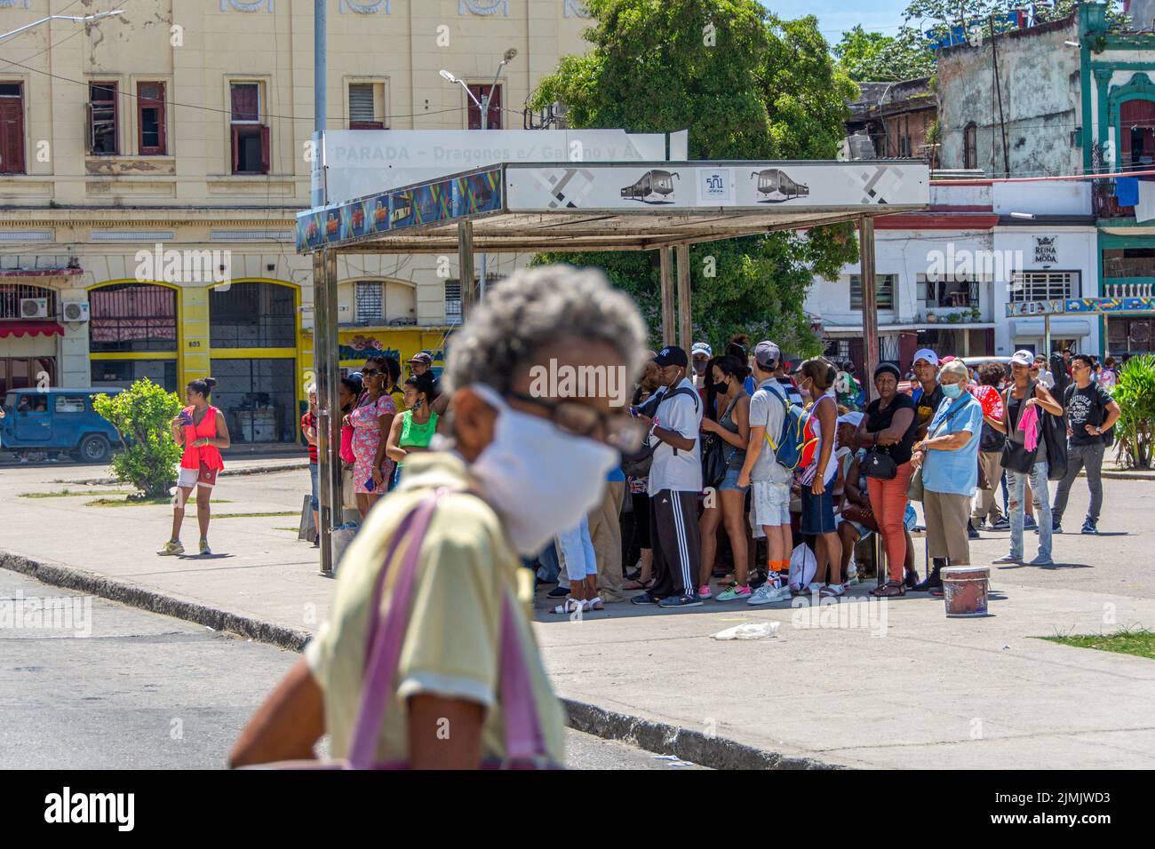 An old, Cuban woman walking in front of a photographer's camera as they photographed a group of ...
