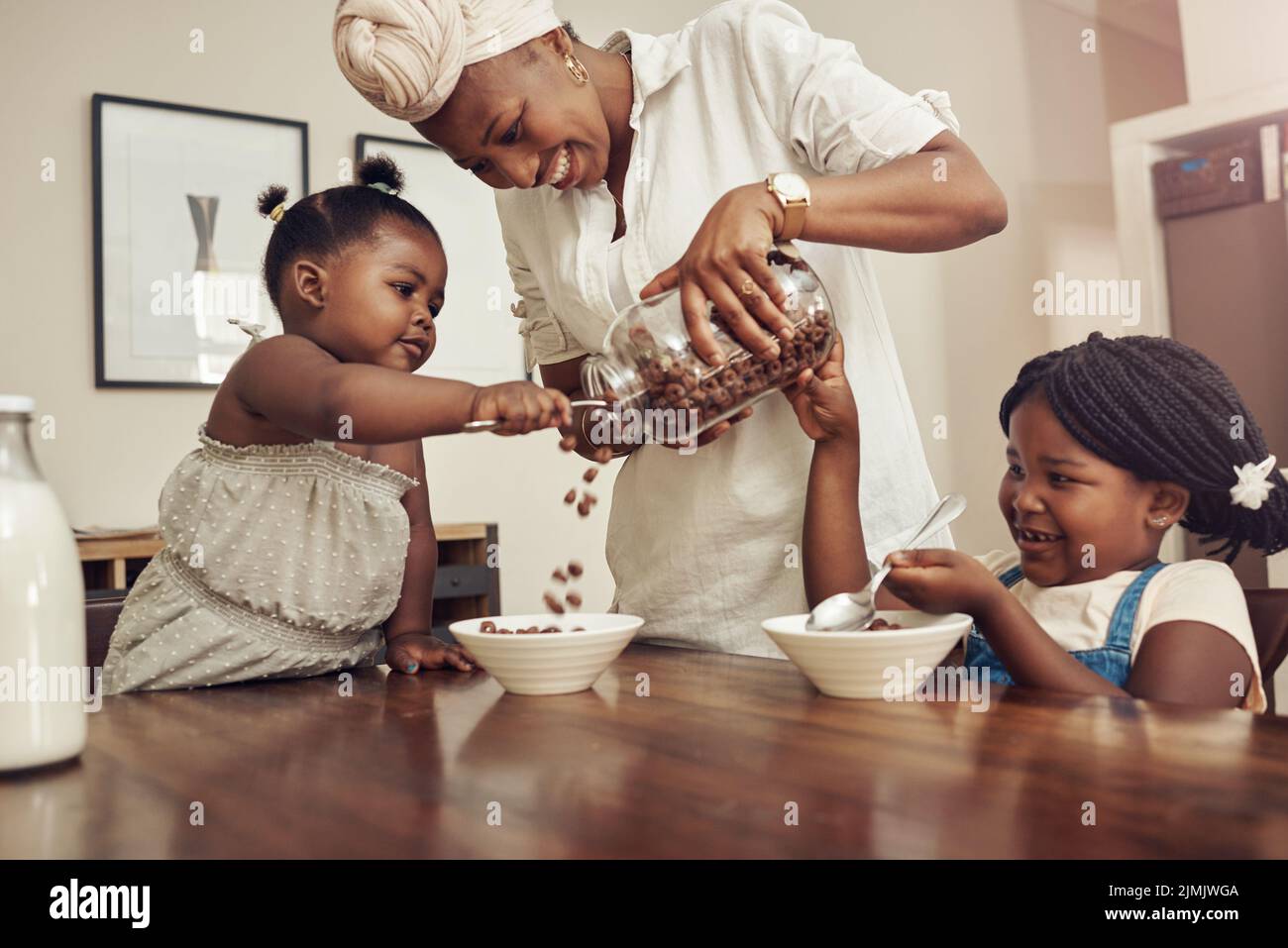 Mommy please add more. a young mother preparing cereal for her two ...