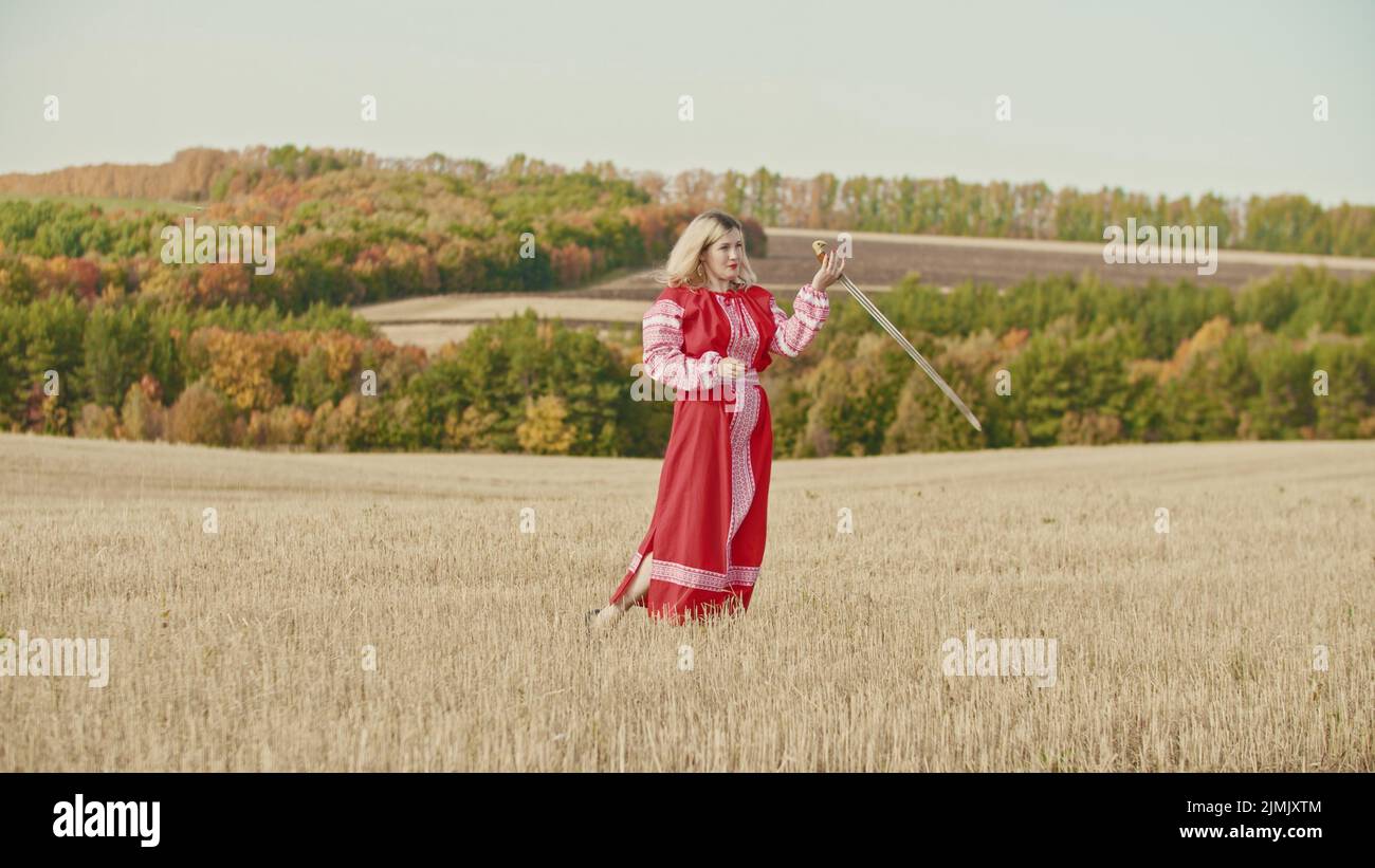 Training in the autumn field - a belligerent woman in red traditional ...