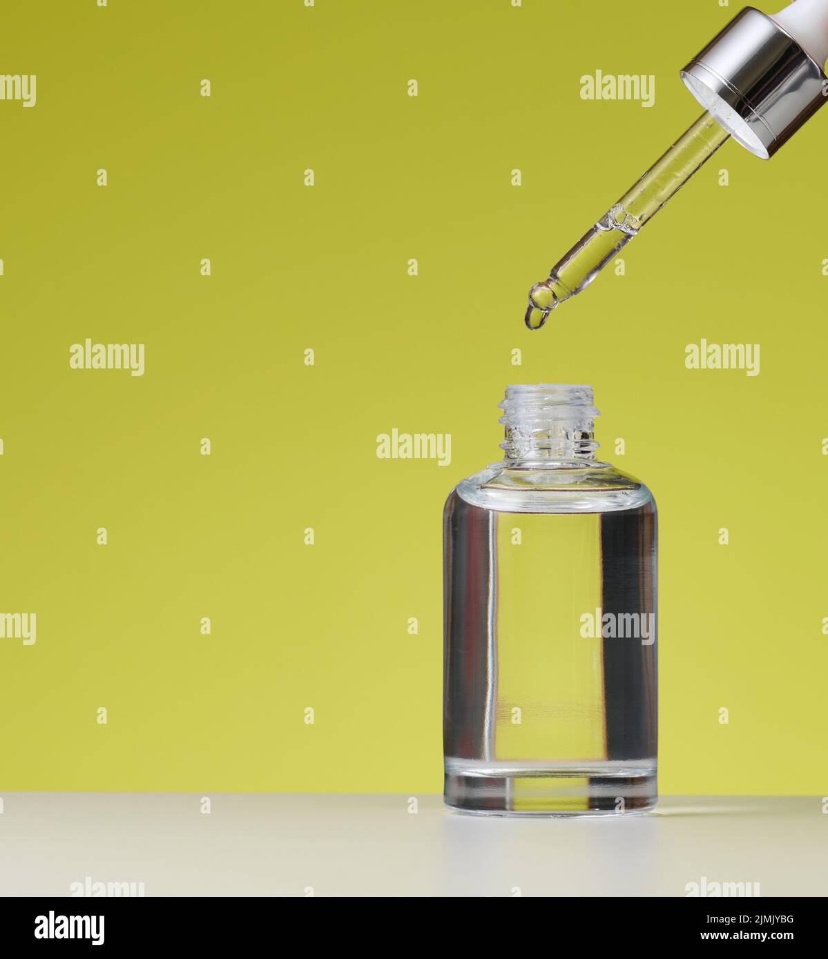 Essential oil falling from the amber glass dropper. White bottle of ...