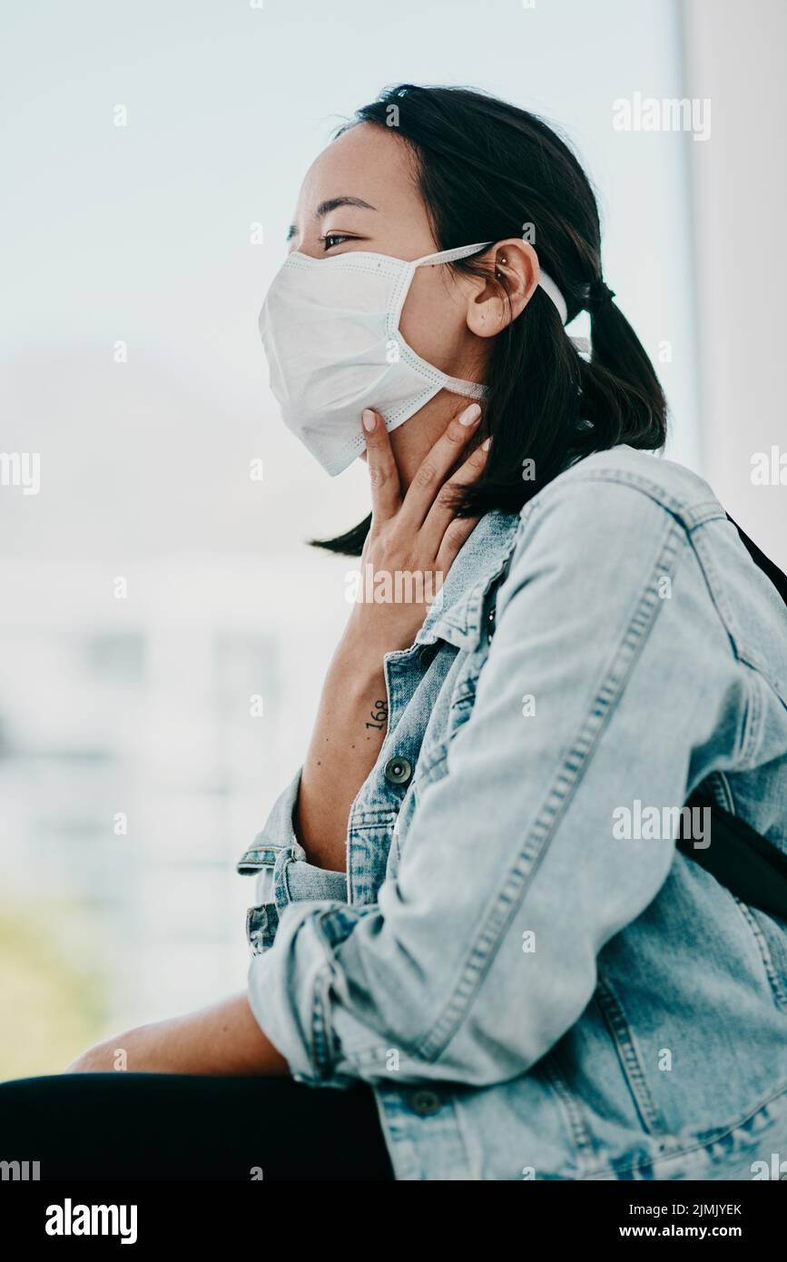 A sore throat is a common symptom of Covid-19. a young woman wearing a ...