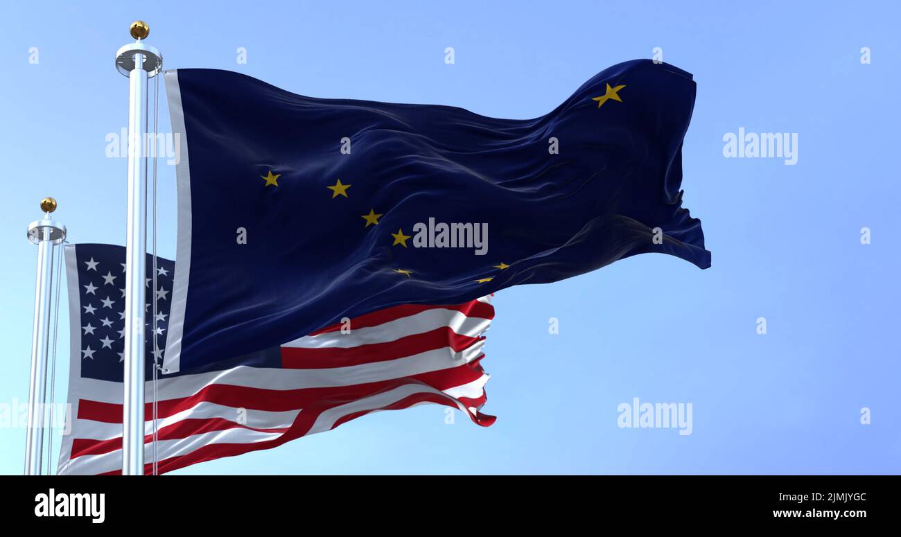 The flags of the Alaska state and United States waving in the wind ...