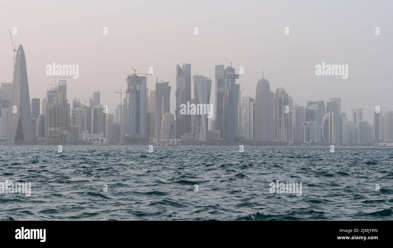 Qatar skyline with rough sea in the foreground on a windy and rainy day ...