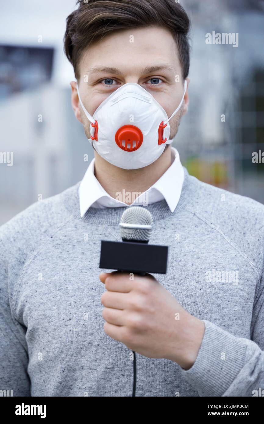 News reporter wearing a prevention mask and speaking into a microphone ...
