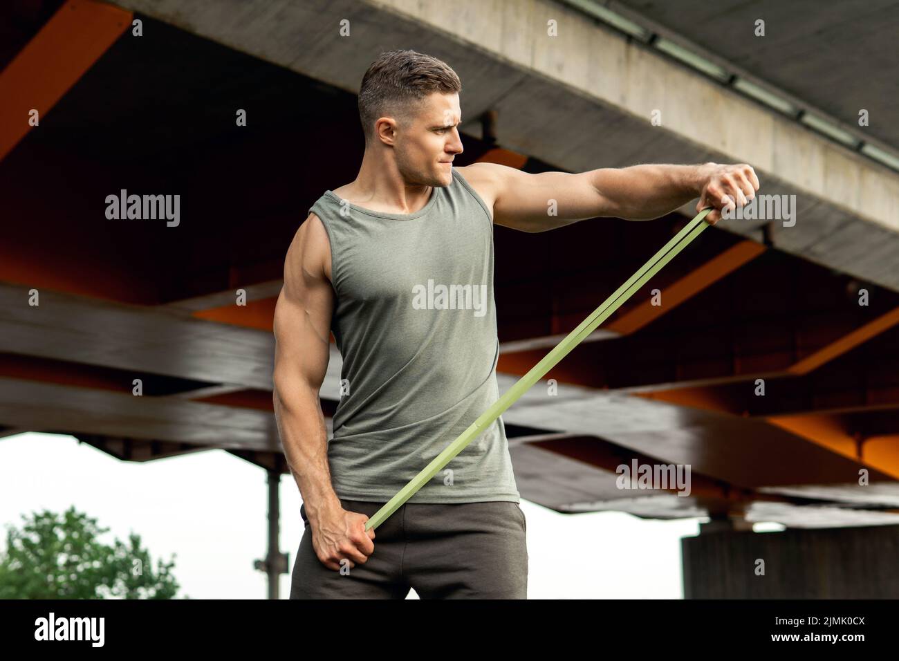 Muscular man during workout with a resistance rubber band on a street ...