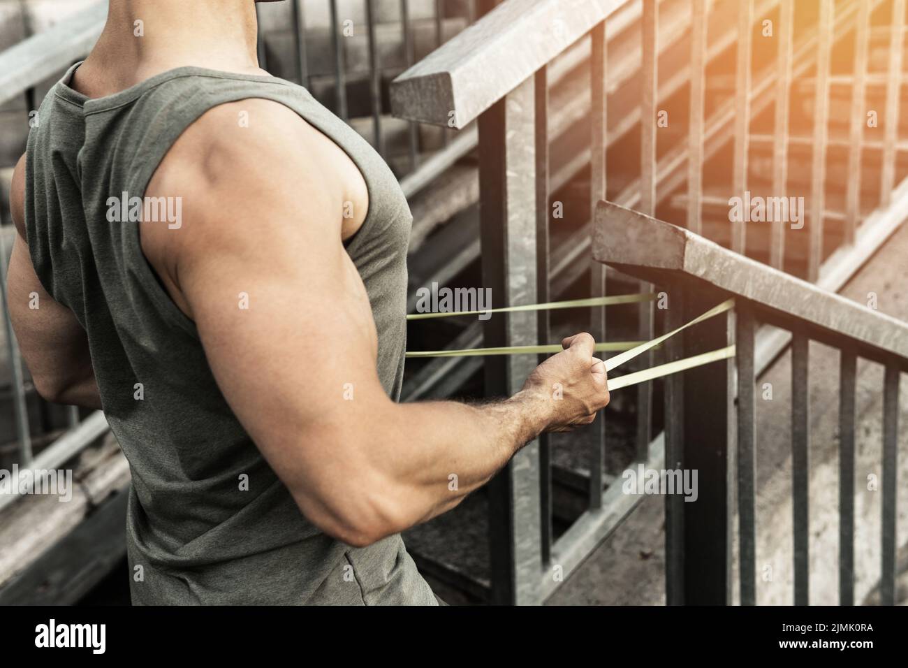 Muscular man during workout with a resistance rubber band on a street ...