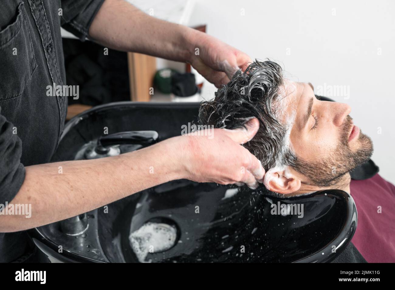 Barber shop. Hairdresser man washes client head in barbershop Stock ...