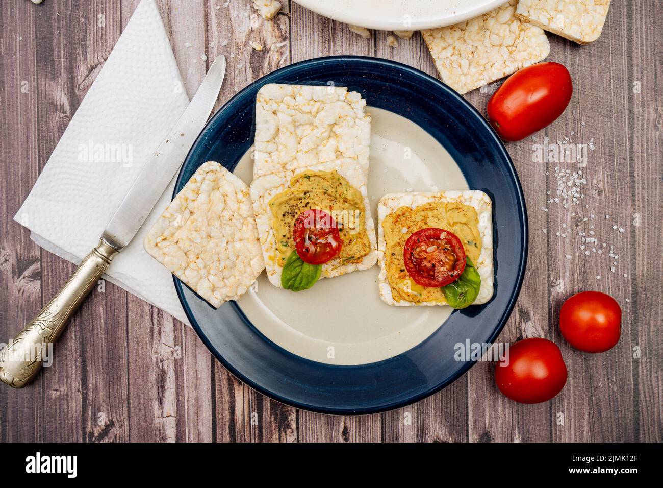 Square rice crackers with hummus and cherry tomatoes on a plate ...