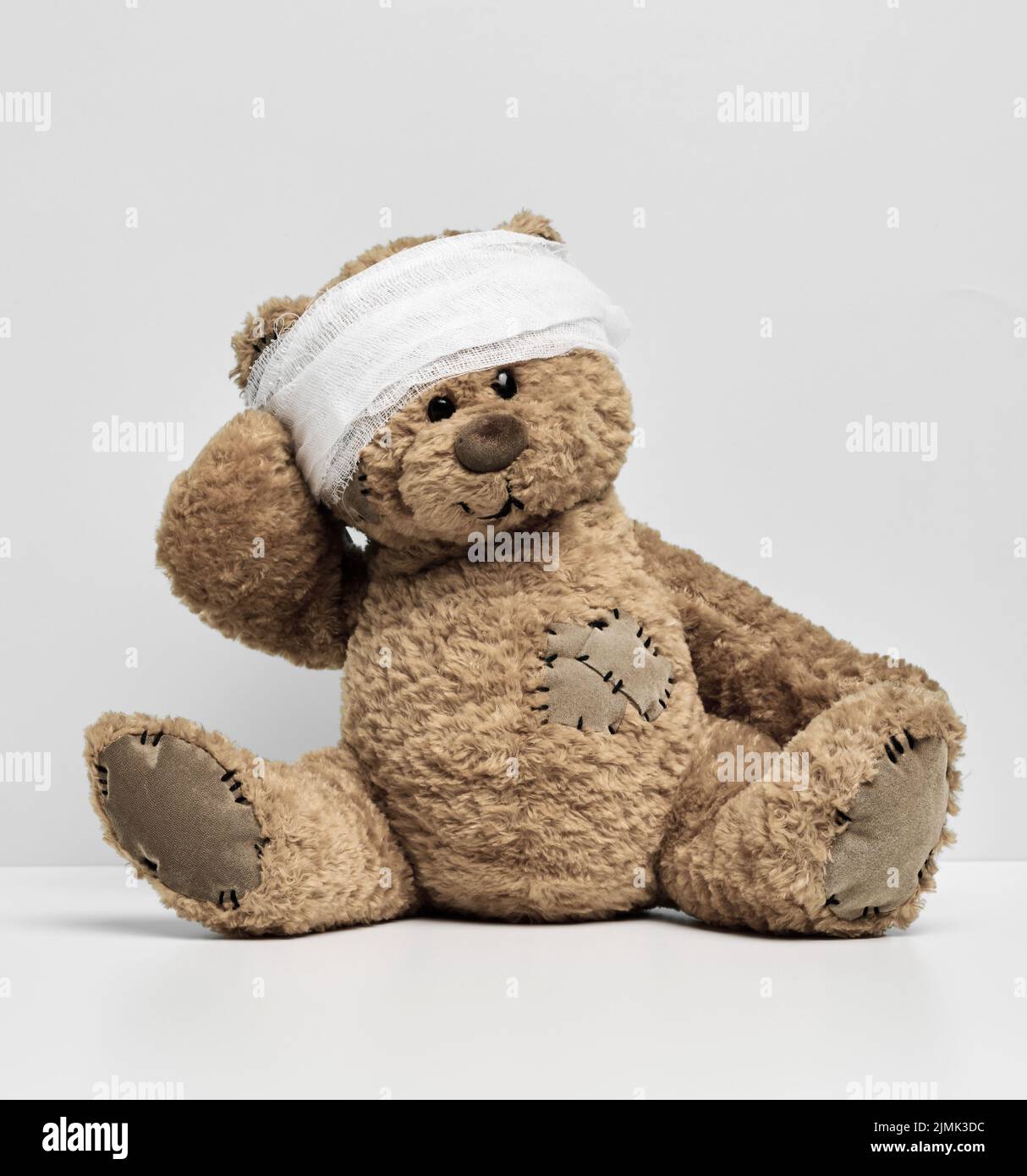 Children's toy teddy bear sits with a bandaged head. Childhood trauma ...