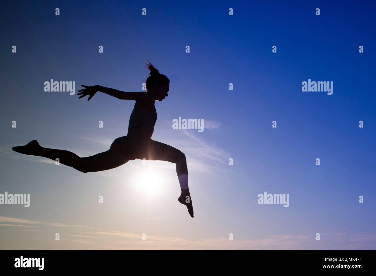 Dance jump performed outdoors in backlight Stock Photo - Alamy