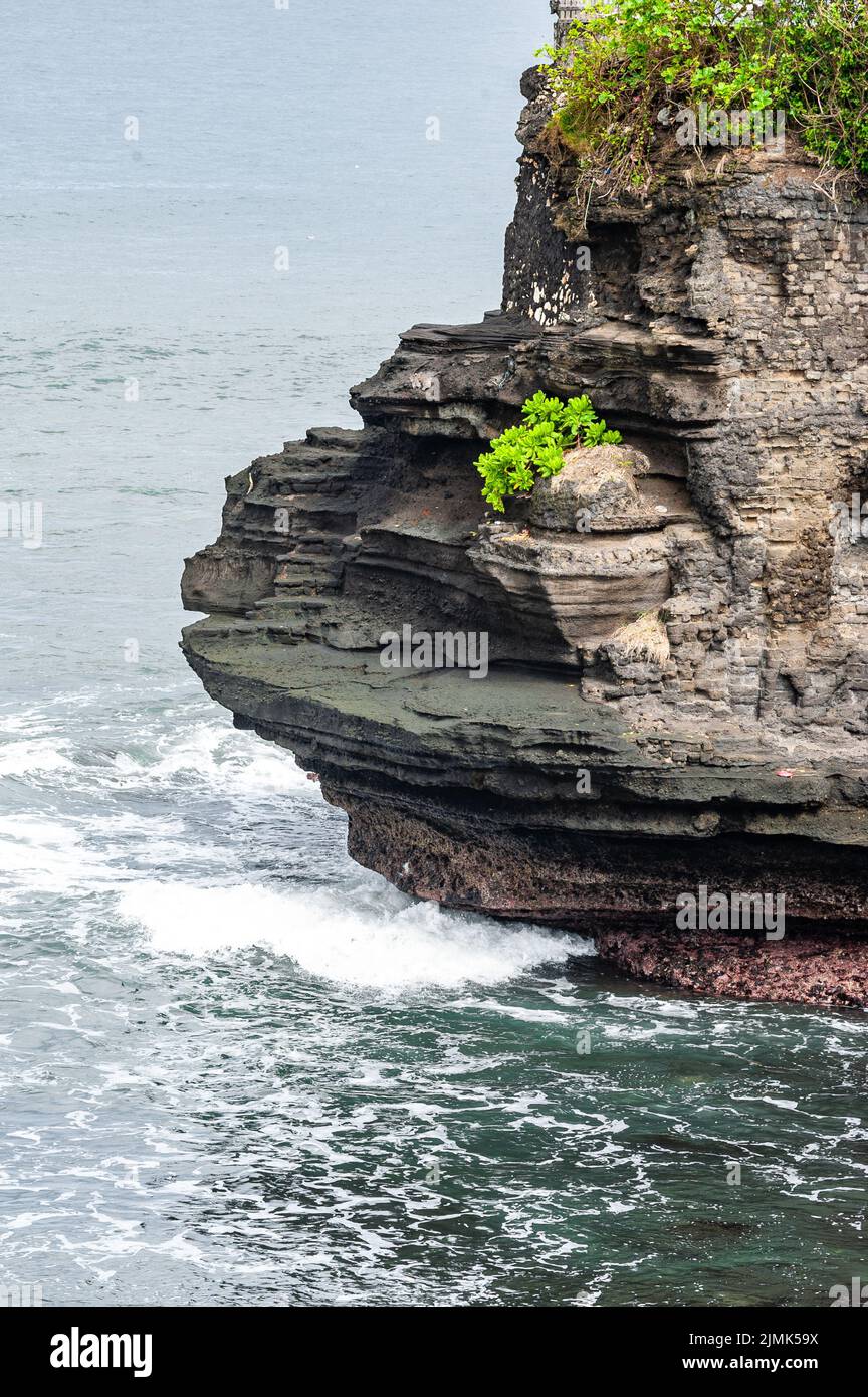 A vertical closeup shot of a cliff near a sea with moving waves - great ...