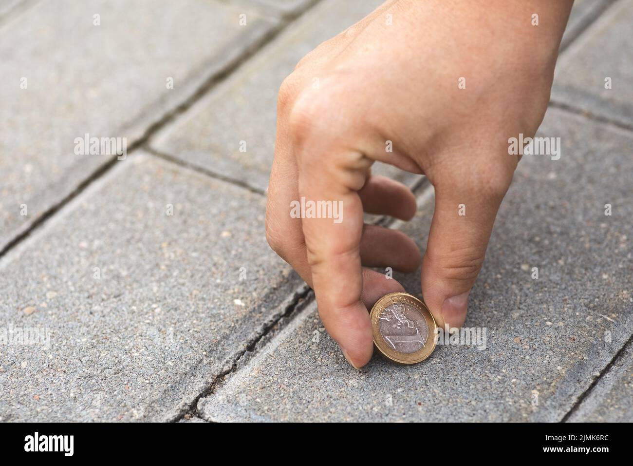 Female hand picking one euro coin from the ground Stock Photo - Alamy