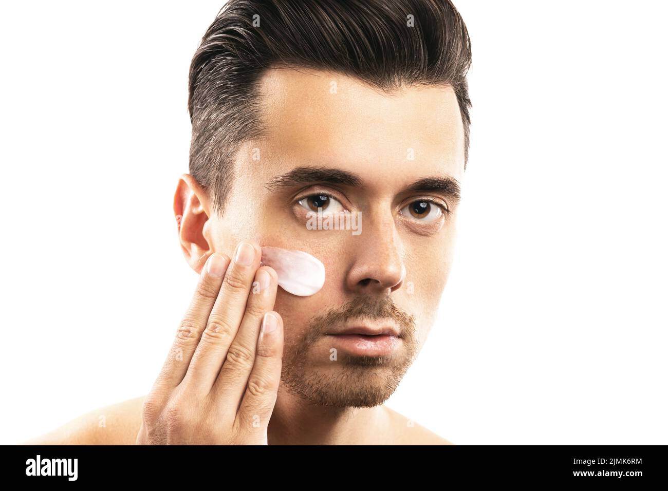 Young man is applying moisturizing cream on his face Stock Photo - Alamy