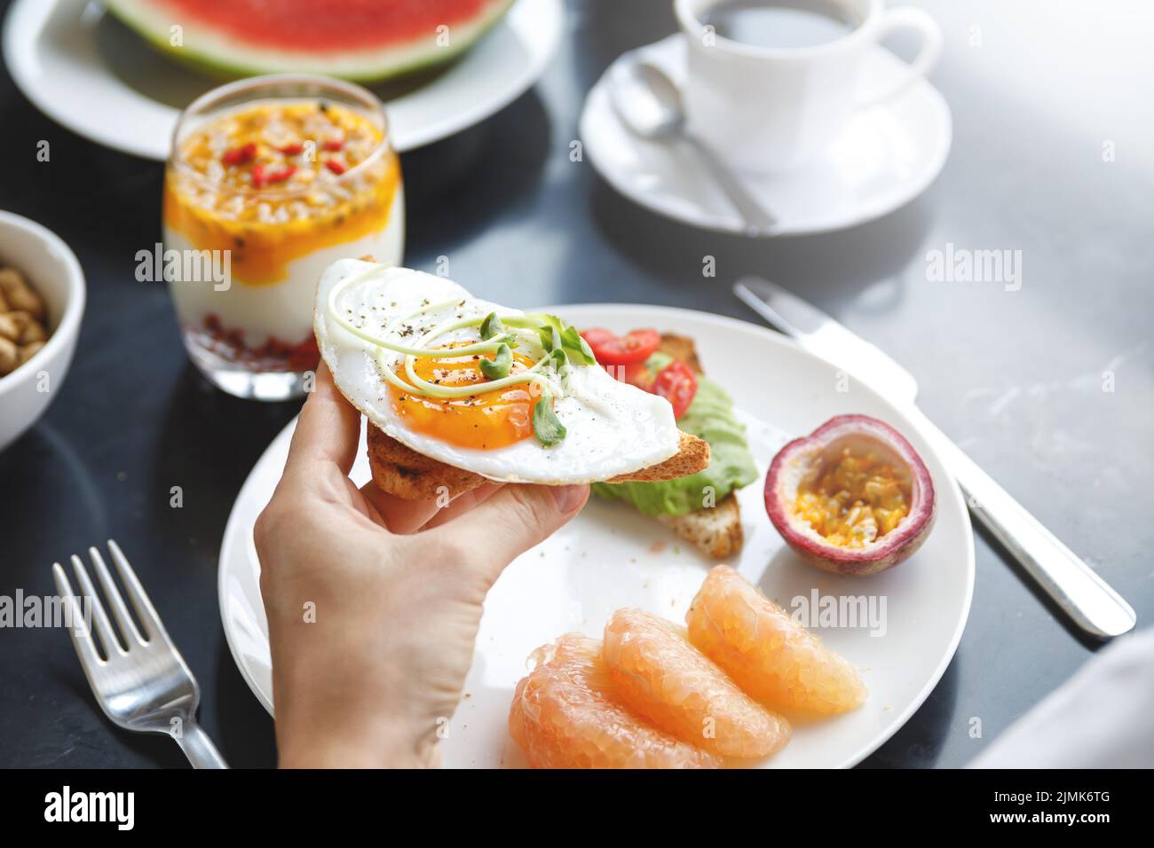 Woman is eating toast with a fried egg Stock Photo - Alamy