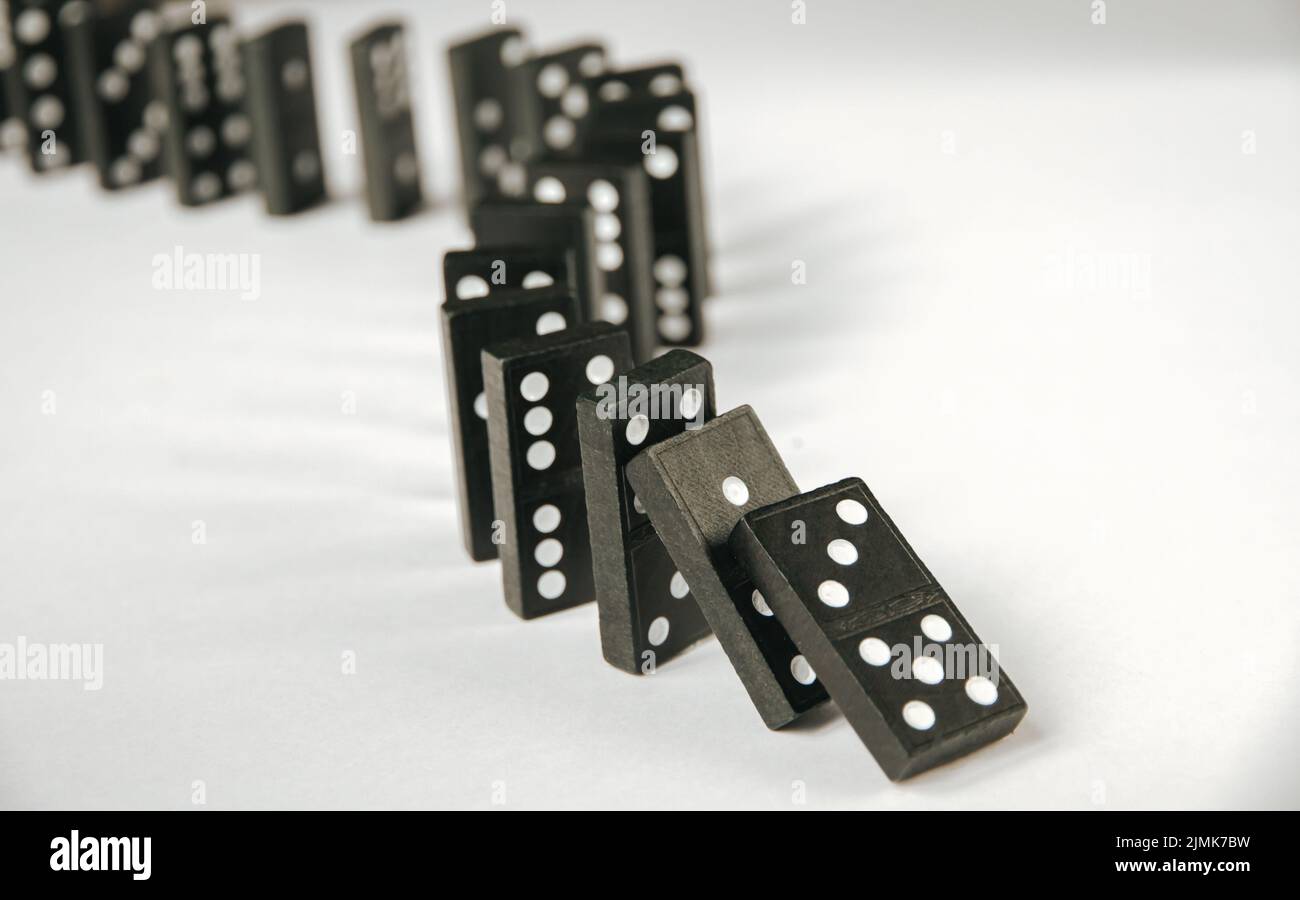 Black dominoes chain on white table background Stock Photo - Alamy