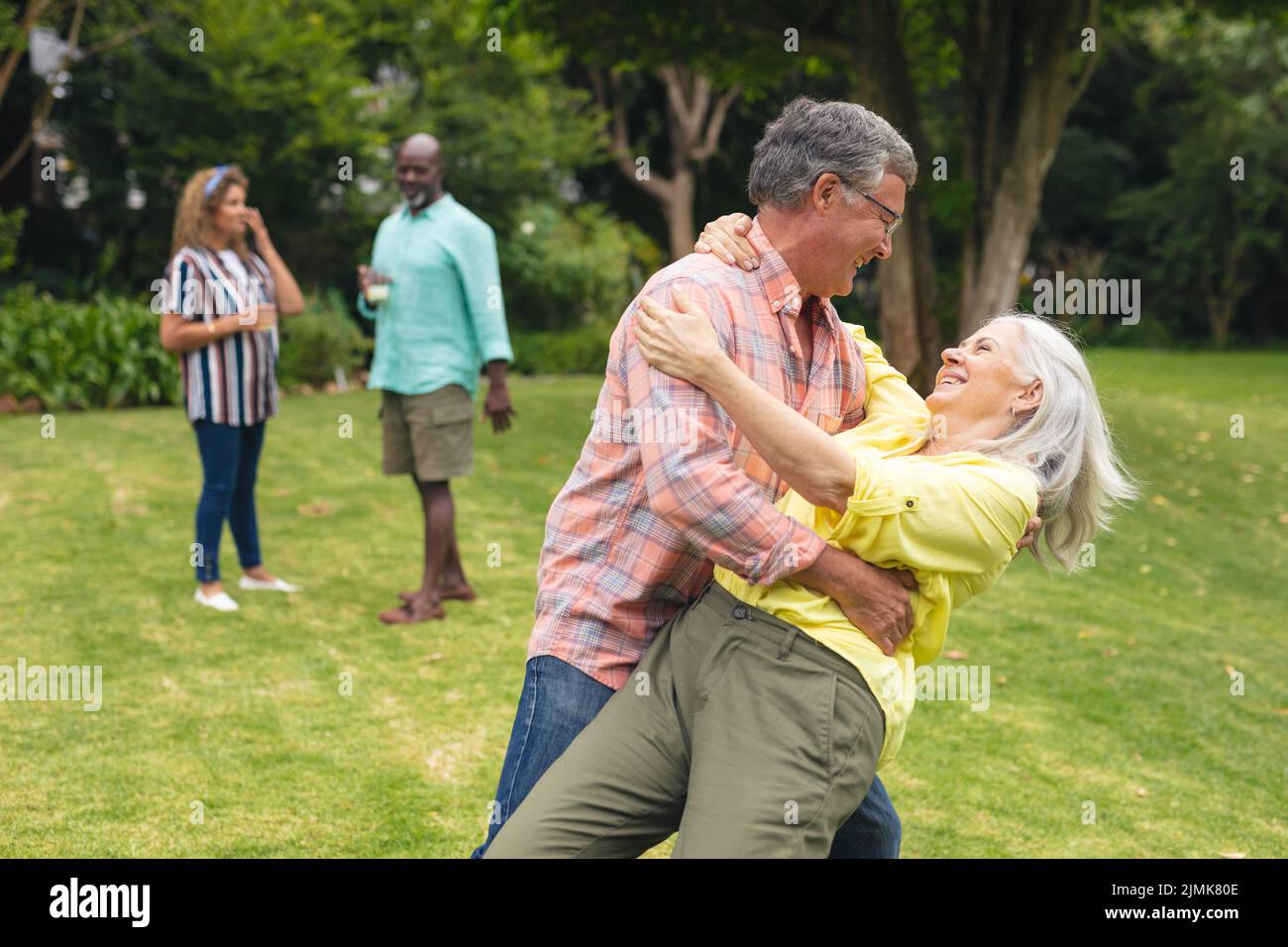 Happy caucasian senior couple dancing while friends in background ...