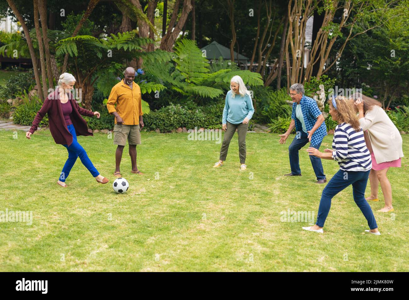 Multiracial active senior male and female friends playing soccer in ...