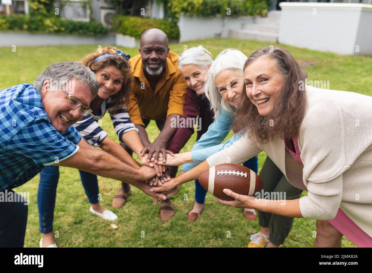 Portrait of smiling multiracial senior male and female friends stacking ...